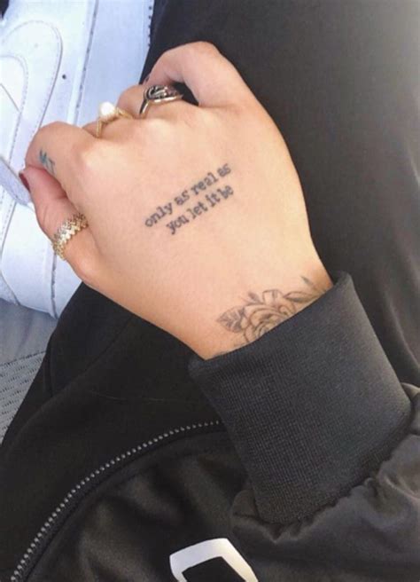 A Person With A Small Tattoo On Their Left Arm Holding A Cell Phone In