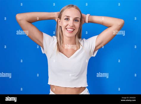 Young Caucasian Woman Standing Over Blue Background Relaxing And Stretching Arms And Hands