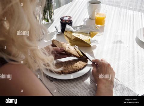 Over Shoulder View Of Mature Woman Spreading Butter Onto Bread Stock