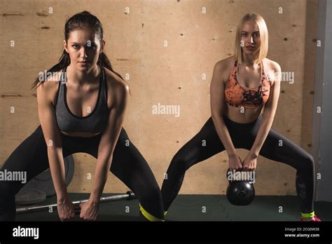 Two Athletic Womans Exercising With Kettle Bell While Being In Squat