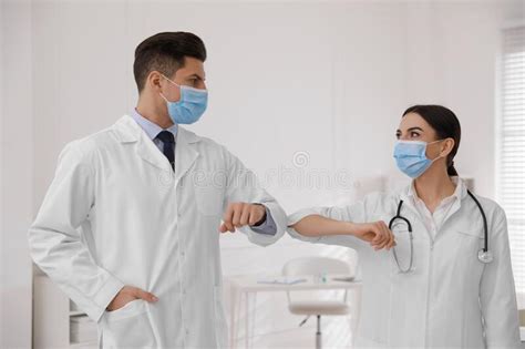 Doctors Greeting Each Other By Bumping Elbows Instead Of Handshake On Light Grey Background