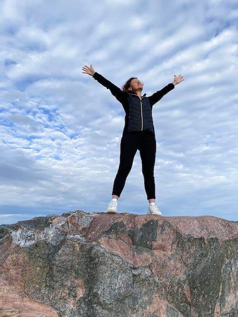 Uma jovem está no topo de uma montanha os braços levantados Foto