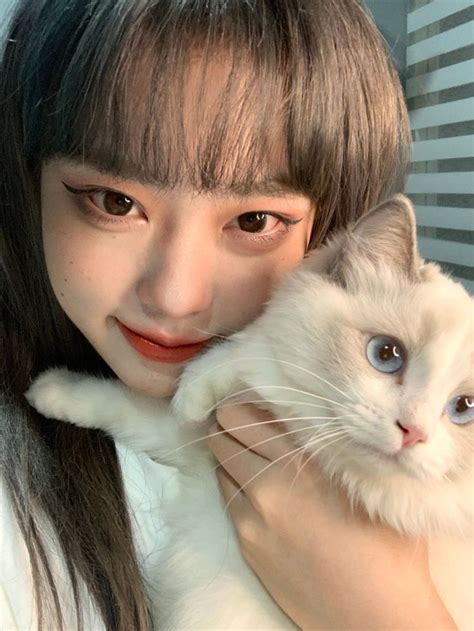 A Woman Holding A White Cat In Her Arms