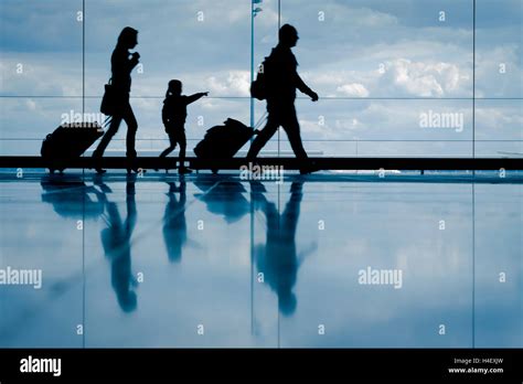 Silhouette der jungen Familie mit Gepäck zu Fuß am Flughafen Mädchen