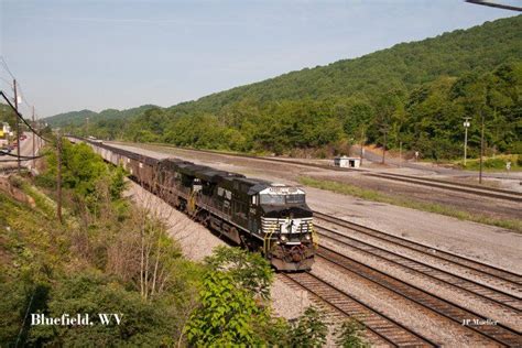 A Train Traveling Down Tracks Next To A Lush Green Hillside