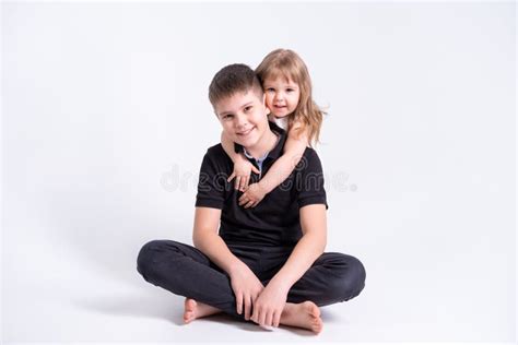 Cute Little Sister Kissing Hugging Her Handsome Older Brother Teenager On White Background Stock