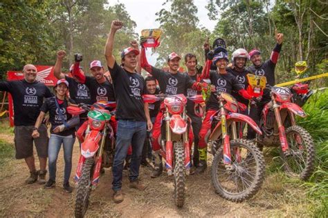 A Group Of People On Dirt Bikes Posing For A Photo With Their Arms In