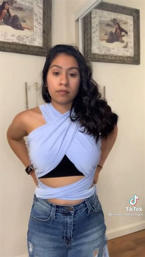 A Woman In Ripped Jeans And A Crop Top Posing With Her Hands On Her Hips