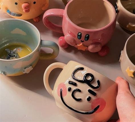 A Person Is Holding A Coffee Mug In Front Of Several Cups With Faces On
