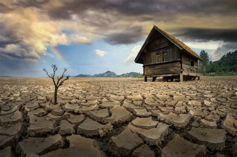 Tierra seca y agrietada en el desierto con cabaña de madera y pequeño