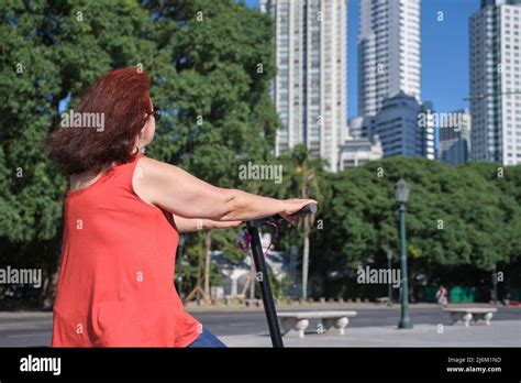 Hispanic Mature Woman Riding Her Electric Kick Scooter Around The City In Summer Concepts Of
