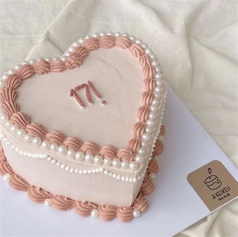 A Heart Shaped Cake With Pearls And Pink Icing On A White Tablecloth
