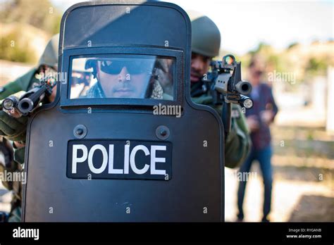 El policía militar apuntando armas desde detrás de un escudo