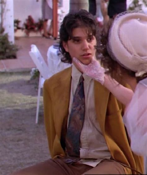 A Man In A Suit And Tie Sitting Next To A Woman Wearing A Dress Hat