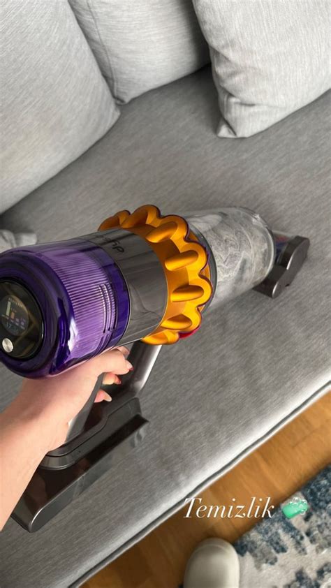 A Person Using A Vacuum To Clean A Couch With A Purple And Yellow Blow