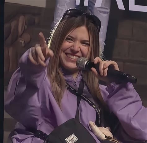 A Woman Holding A Microphone In Her Right Hand And Pointing To The Side