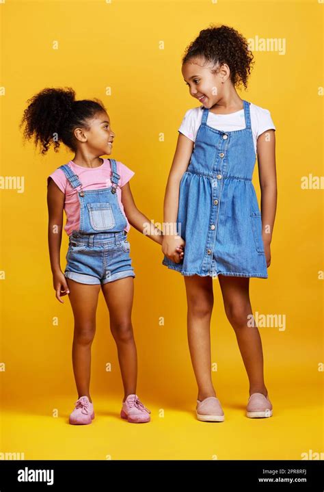 Mixed Race Girl Sisters Holding Hands Isolated Against A Yellow Background Cute Hispanic