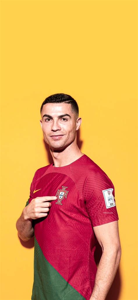 A Man Standing In Front Of A Yellow Wall Wearing A Red And Green Soccer