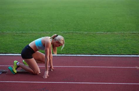 Grupo De Mujeres Atletas Corriendo En La Pista De Carreras De Atletismo