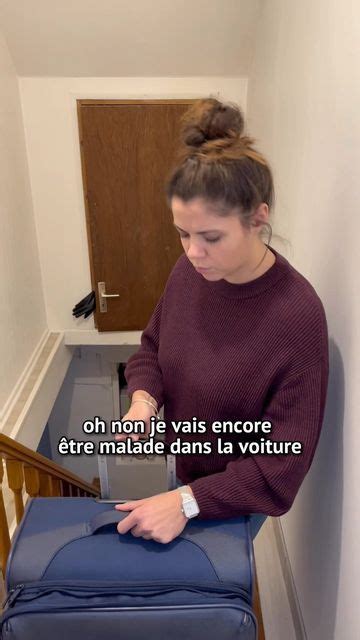 A Woman Standing Next To A Blue Piece Of Luggage In A Hallway With The