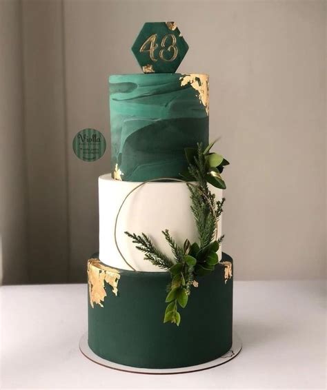 A Three Tiered Cake With Green And Gold Decorations