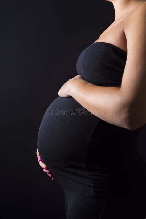 Soporte De La Mujer Embarazada Con Las Manos En El Vientre Foto De