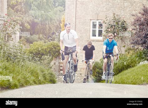 Cyclists Riding Through Village Cotswolds Uk Stock Photo Alamy