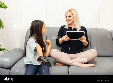 buena relación linda niña con joven madre usando joystick jugando juego
