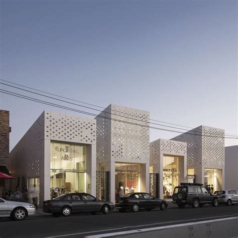 Several Cars Parked In Front Of A Building With Perfored Panels On The Side