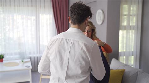 Mother Helping Her Businessman Son Who Is Late For Work A Mother Helping Her Son Who Is Late