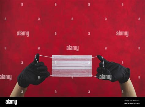 Las manos con guantes protectores estiran una máscara médica sobre