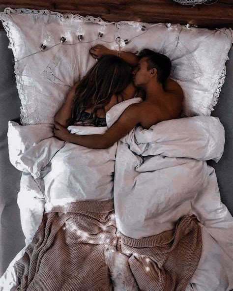 Two People Laying In Bed With White Sheets And Blankets On Top Of Eachother