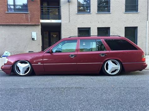 A Maroon Station Wagon Parked In Front Of A Brick Building With White