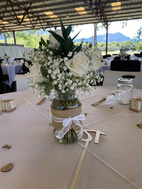 A Vase Filled With White Flowers Sitting On Top Of A Table Covered In