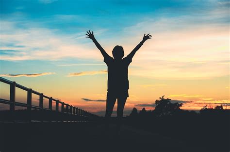 Feliz celebrando mulher vencedora de sucesso ao pôr do sol ou nascer do