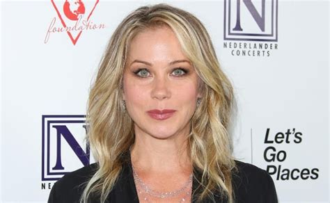 A Woman With Blonde Hair Wearing A Black Blazer And Blue Eyeshadow Is
