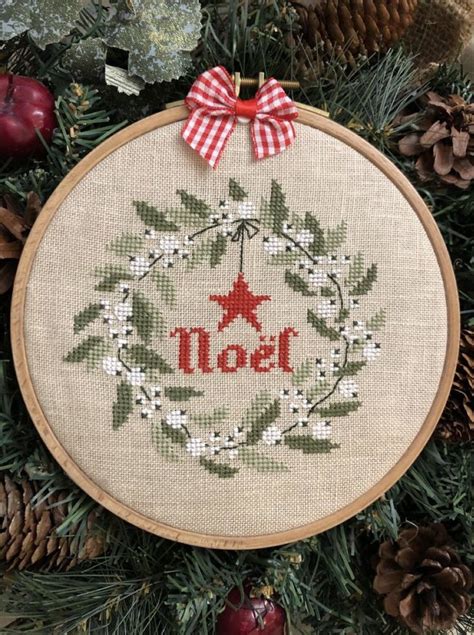 A Cross Stitch Christmas Ornament Hanging From A Tree