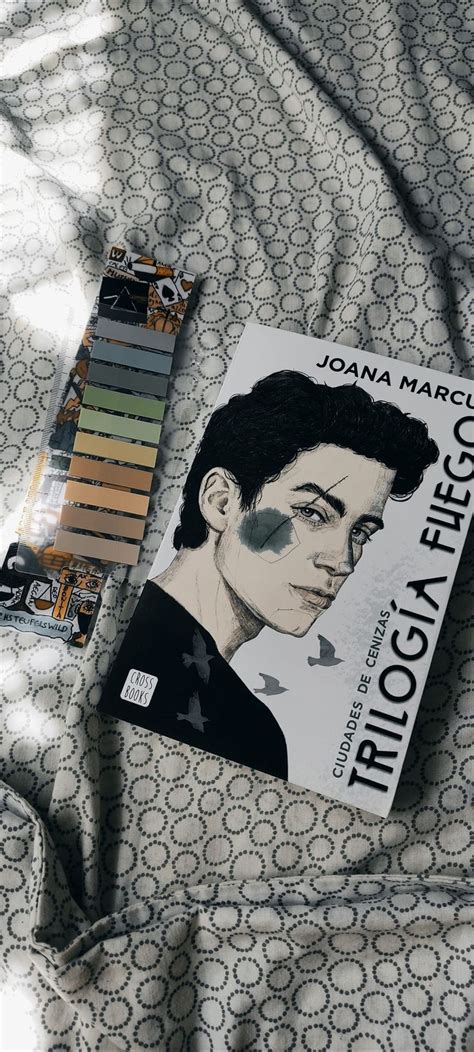 A Book Sitting On Top Of A Bed Next To A Pair Of Eyeliners