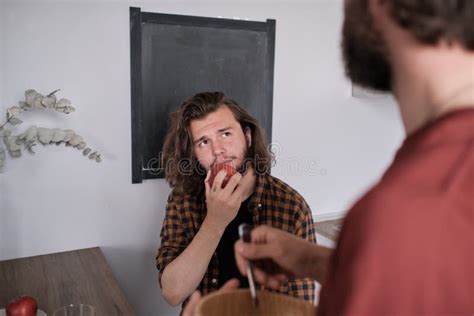 Bearded Man Eating Apple While Talking To His Friend Stock Photo