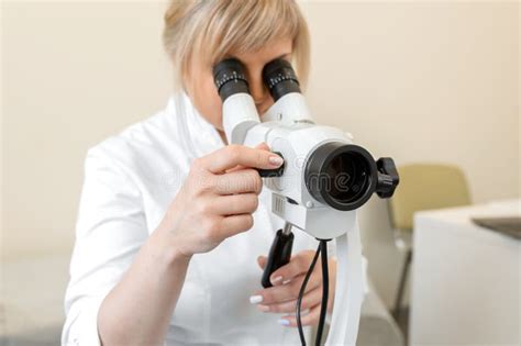 Female Blond Doctor Gynecologist Looks Through A Colposcope Examination By A Gynecologist Stock
