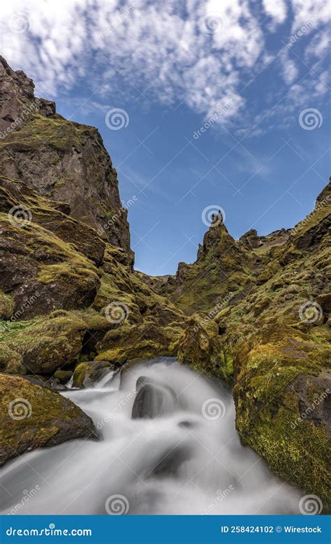 Vertical Shot Of The River Flowing Between Mossy Rocks Stock Photo