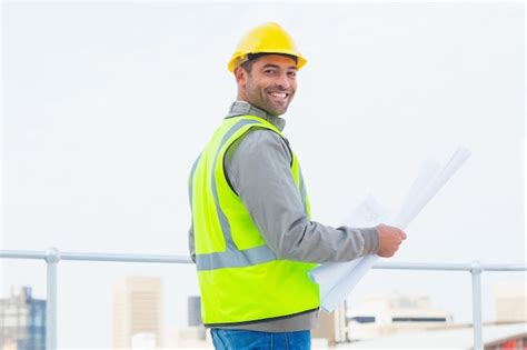 Arquitecto en ropa de protección con blueprint al aire libre Foto Premium