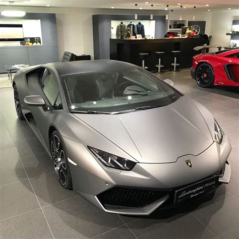 A Silver Sports Car Parked In A Showroom Next To Another Red Sport Car