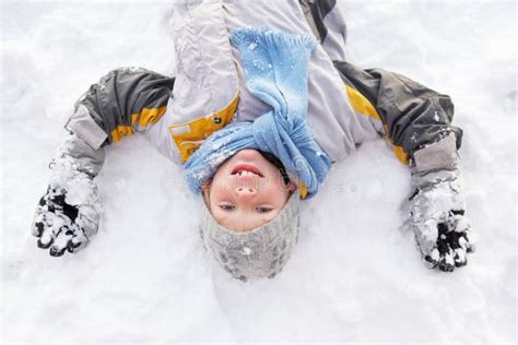 Menino Que Coloca No Anjo De Factura à Terra Da Neve Imagem de Stock