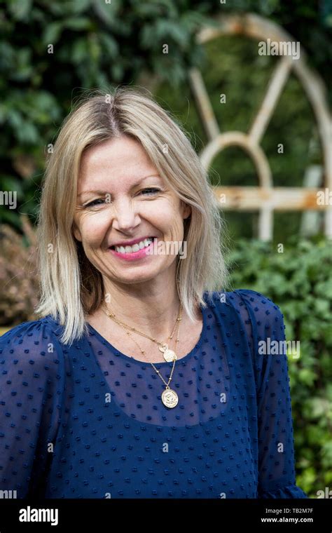 Woman With Blond Hair And Wearing Blue Top Standing Outdoors Smiling
