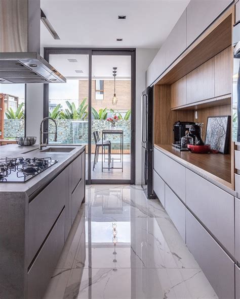 Cozinha cinza e amadeirada ilha em lâmina porcelânica e tv