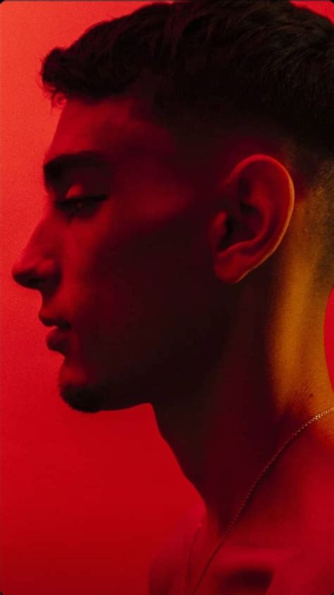 A Man With His Head Turned To The Side Wearing A Necklace And Looking