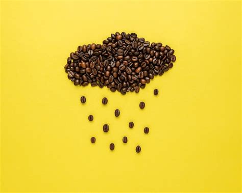 Granos de café en forma de nube lluviosa sobre superficie amarilla