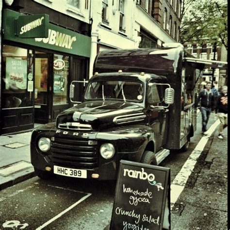 An Old Truck Is Parked On The Side Of The Road In Front Of A Restaurant