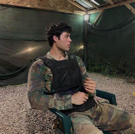 A Man Sitting In A Chair Next To A Black Object On Top Of Gravel